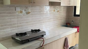 Um frigorífico, um micro-ondas, utensílios de cozinha, mesas de jantar