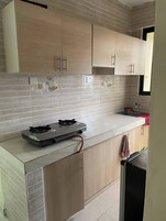 Um frigorífico, um micro-ondas, utensílios de cozinha, mesas de jantar 