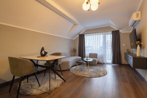 Uma sala de estar moderna com área de jantar, um sofá, uma mesa de centro e uma televisão em um suporte.