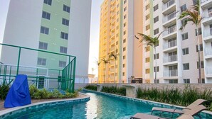 Piscina com espreguiçadeiras, rodeada por edifícios residenciais altos.