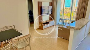 Uma sala de estar moderna com área de refeições, TV e varanda com vista.