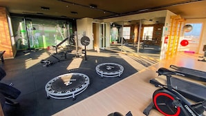 Uma academia com equipamentos de ginástica, esteira e espelho.