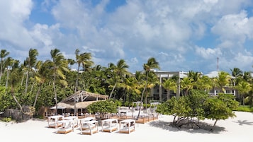 Praia particular, areia branca, espreguiçadeiras, guarda-sóis