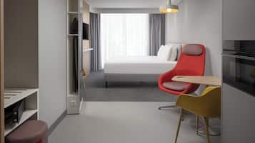 Quarto de hotel moderno com uma cama, uma cadeira vermelha, uma cadeira amarela, uma mesa pequena e uma televisão.
