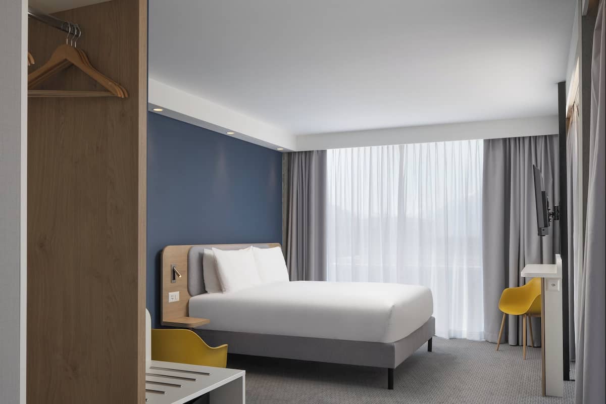 Quarto de hotel moderno com uma cama, uma escrivaninha e uma cadeira.