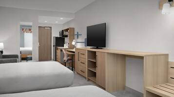 Quarto de hotel moderno com uma cama grande, uma escrivaninha com televisão de tela plana, uma cadeira e um guarda-roupa.