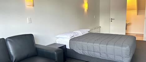 Quarto com cama, sofá e duas luzes fixadas na parede.