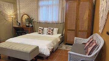 Quarto com cama, mesa de cabeceira, abajur, cadeira, guarda-roupa e cortinas.