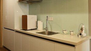 Uma cozinha moderna com armários brancos, uma pia de aço inoxidável e um exaustor embutido.