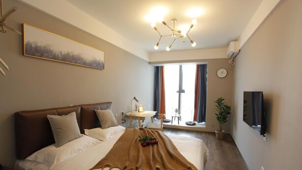 Quarto de hotel com uma cama grande, uma escrivaninha, uma cadeira, uma televisão e uma janela com cortinas.