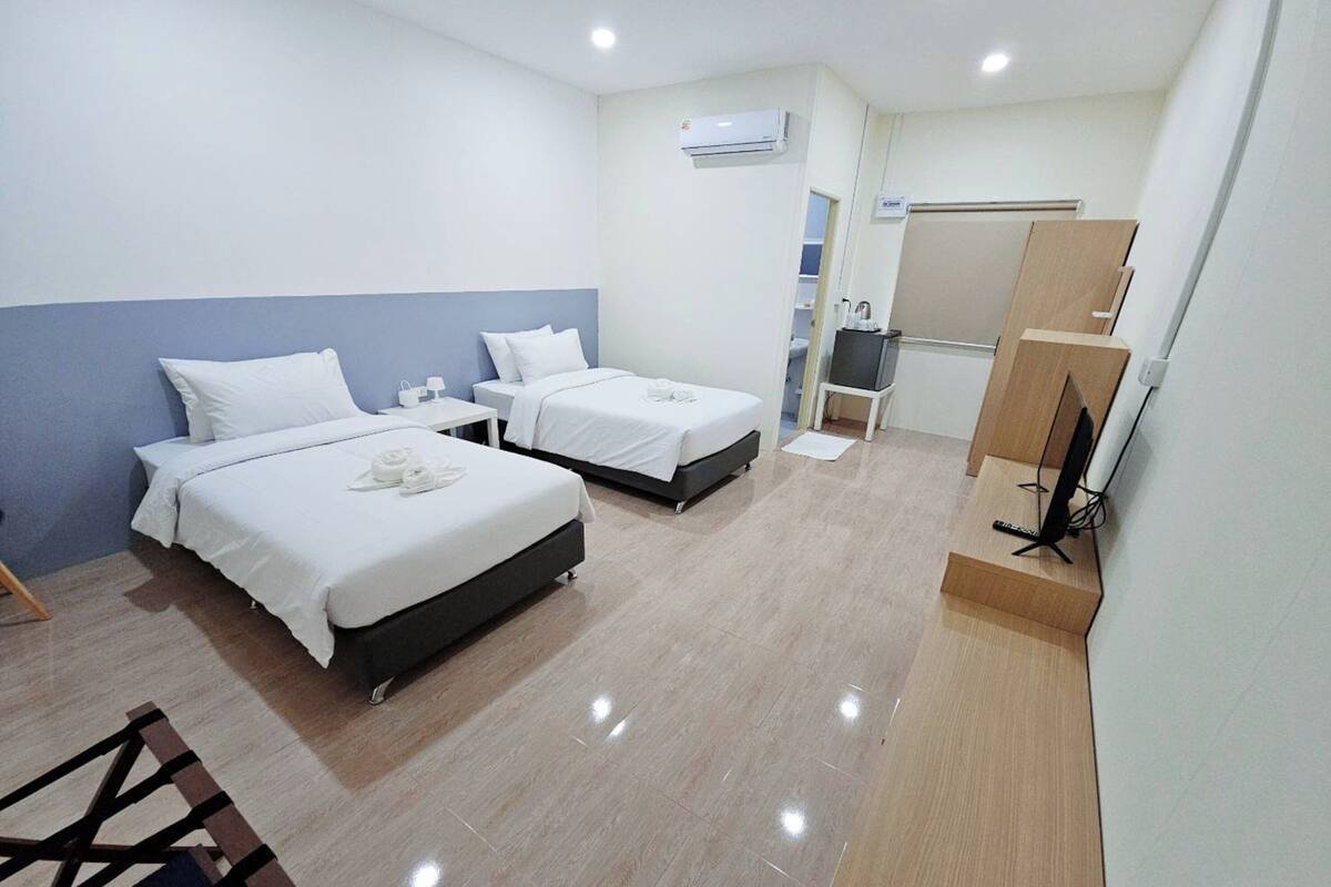 Quarto de hotel com duas camas, uma escrivaninha, uma televisão e um aparelho de ar condicionado.