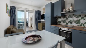 Cozinha moderna com ilha branca, armários azuis e vista para o exterior.