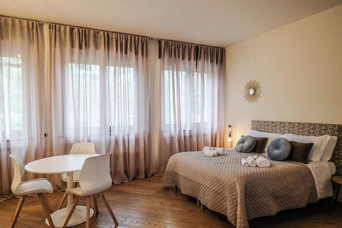 Um quarto com cama, mesa de cabeceira e uma cadeira.
