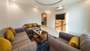 Uma sala de estar moderna com um conjunto de sofá, uma mesa de centro e uma TV fixada na parede.