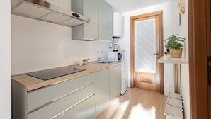 Cozinha moderna com bancada de madeira, eletrodomésticos de aço inoxidável e armários em tons claros.