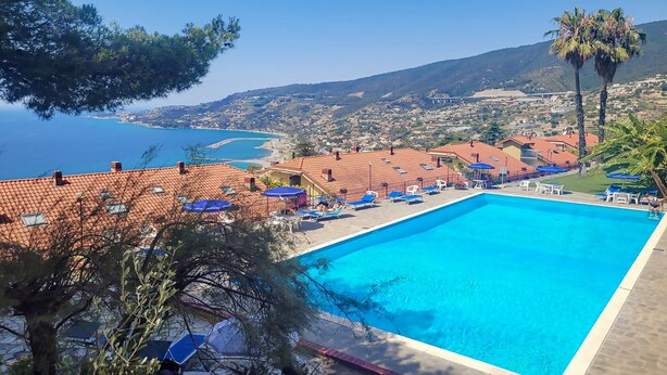 Piscina com vista para o mar e uma cidade ao fundo.