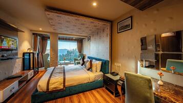 Quarto de hotel moderno com uma cama grande, uma escrivaninha, uma televisão e vista para as montanhas.