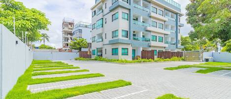 Um edifício residencial moderno de vários andares, com telhado plano, janelas amplas e varandas nos andares superiores.