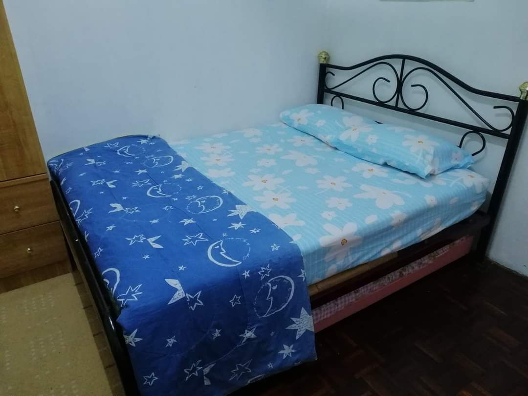 Uma cama de solteiro com colcha e travesseiro floridos em azul e branco.