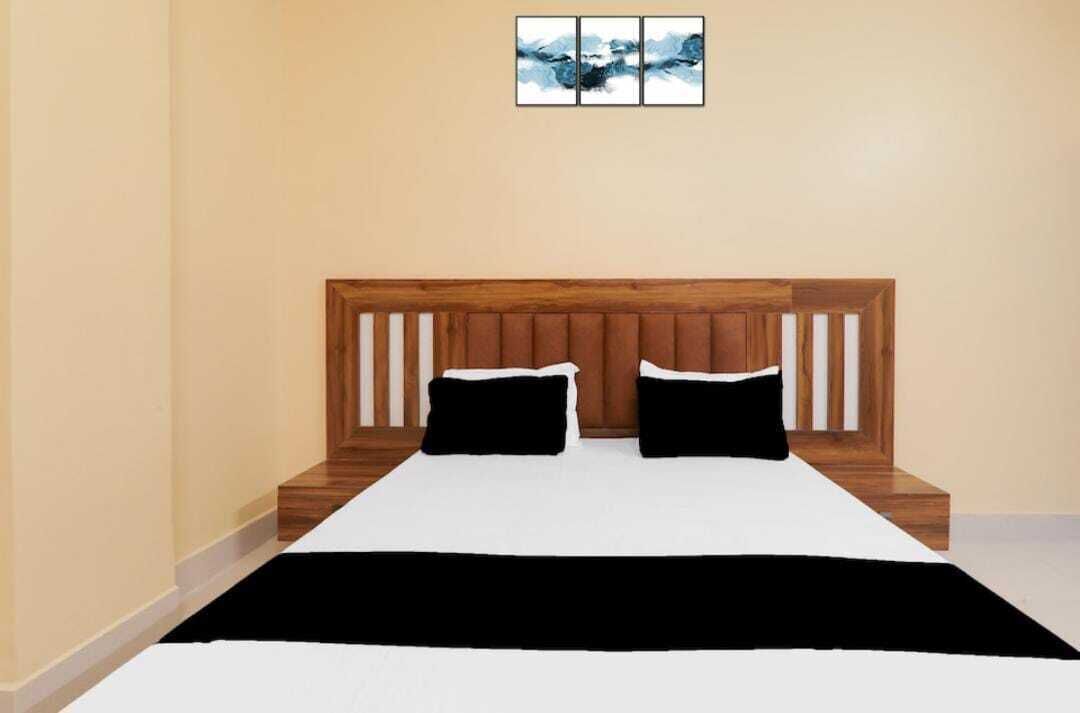 Quarto com cabeceira de madeira, duas almofadas pretas e colcha branca.
