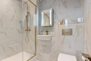 Uma casa de banho moderna com chuveiro de vidro, lavatório assentado e espelho fixado na parede.
