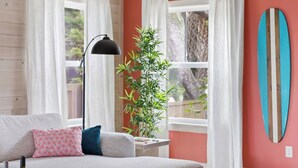 Um quarto com uma cama, uma luminária, uma planta e uma prancha de surf na parede.