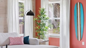 Um quarto com uma cama, uma luminária, uma planta e uma prancha de surf na parede.