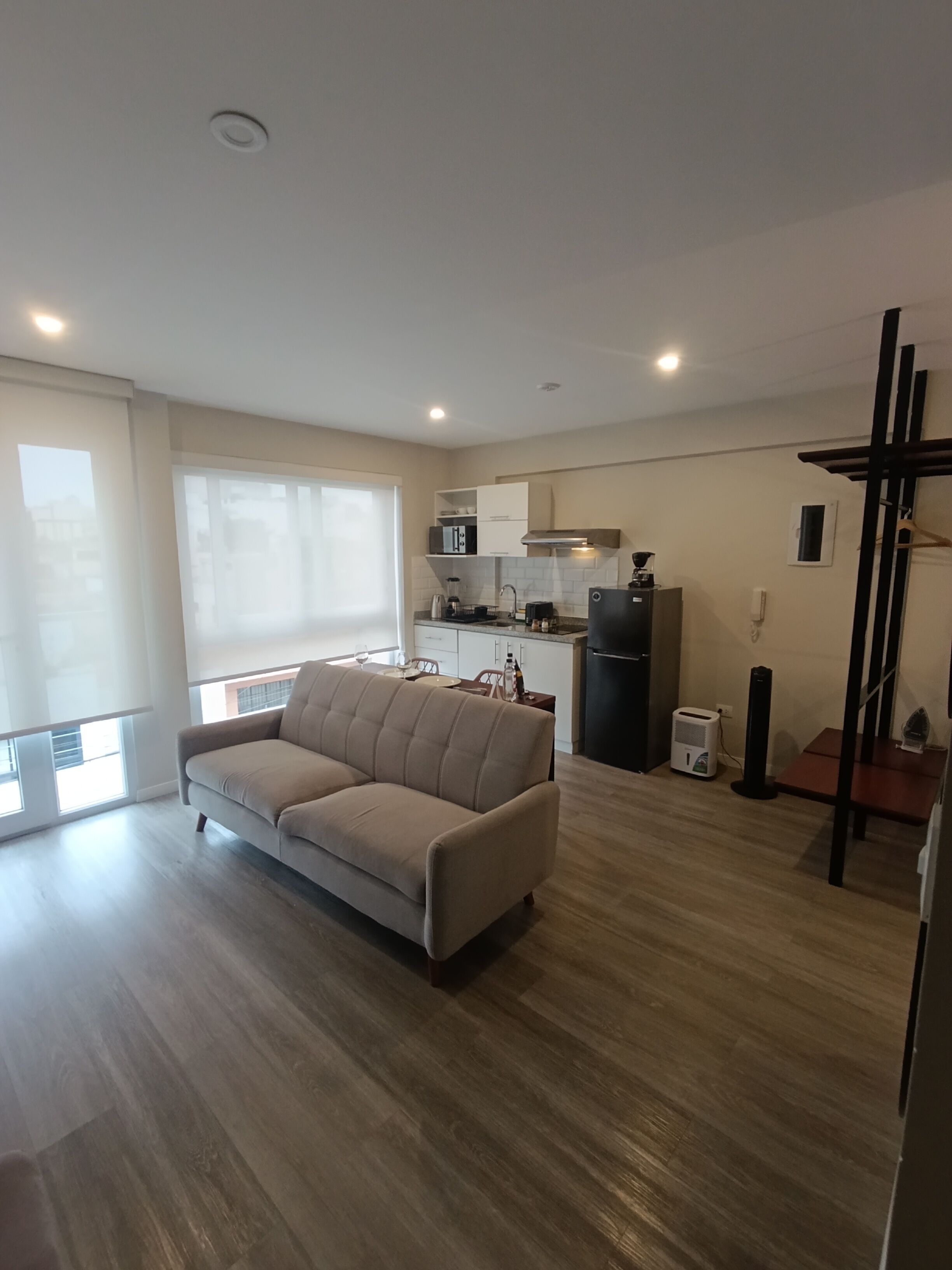 Uma sala de estar moderna com sofá, cozinha equipada e mesa de jantar.