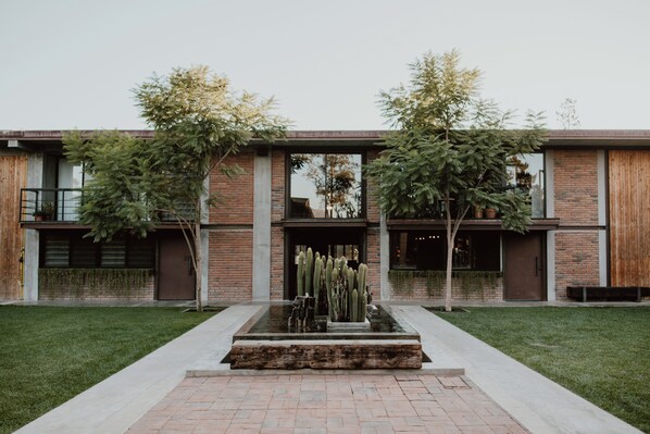 Um edifício moderno com fachada de tijolos, um pátio central com jardim de cactos e duas árvores.