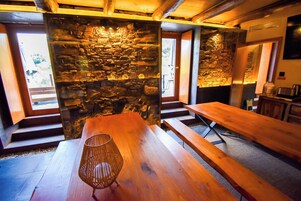 Um interior moderno com uma mesa de madeira, uma cadeira trançada e uma parede de pedra.