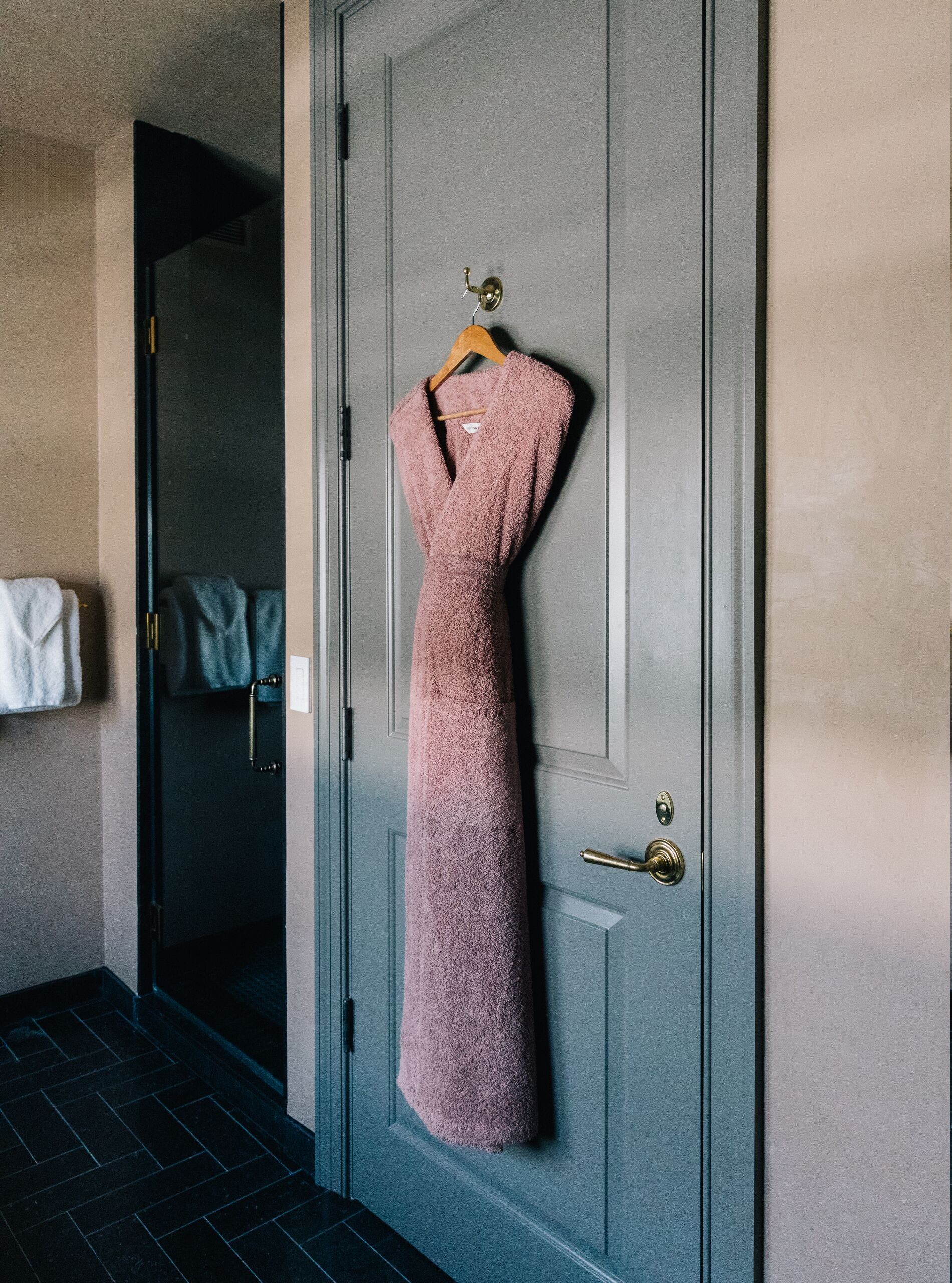 Um vestido rosa comprido pendurado numa porta em um corredor.