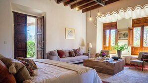 Quarto com uma cama grande, um sofá, uma mesa de centro e vista para o exterior.