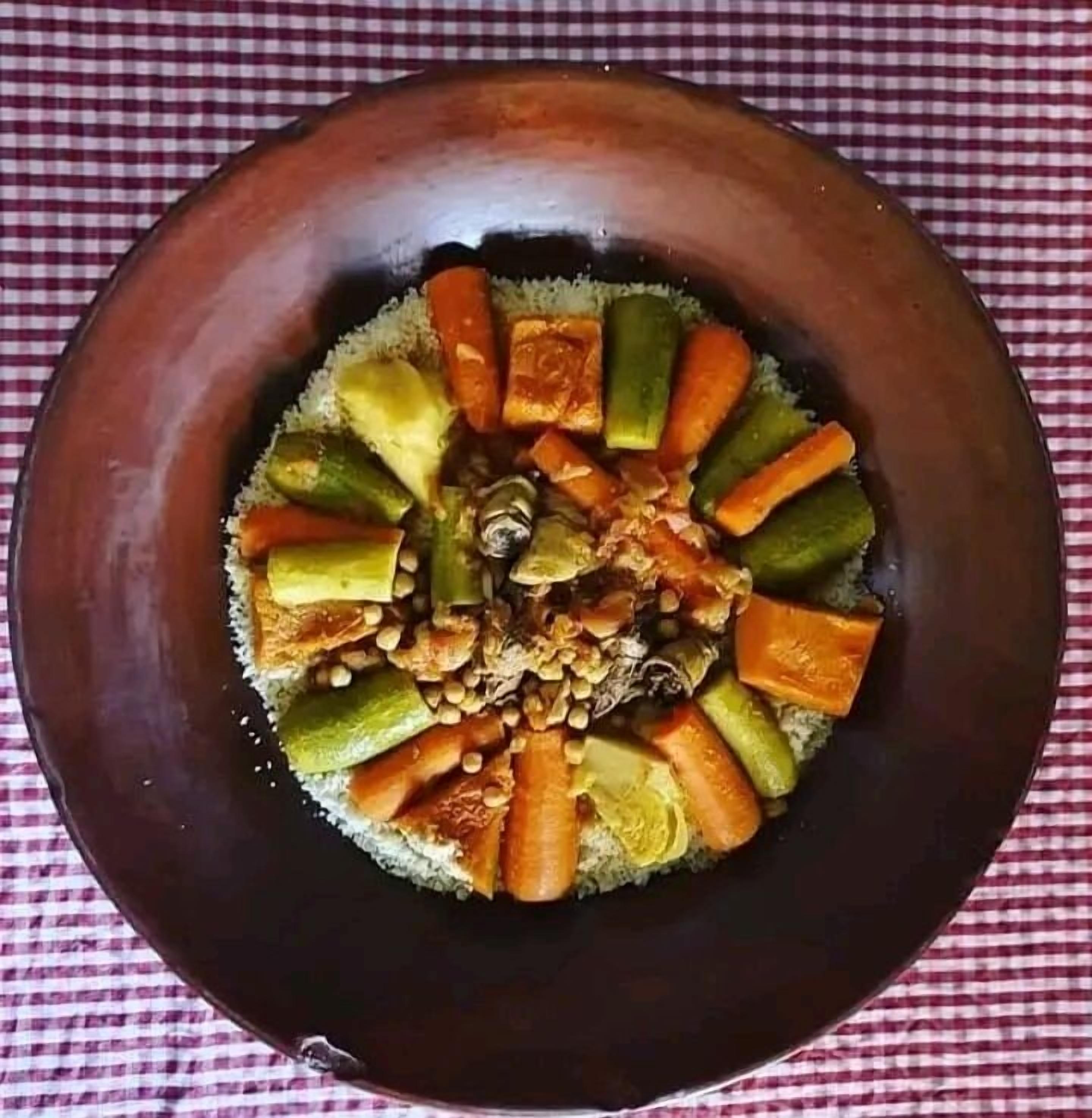 Um prato marrom escuro com um prato de legumes coloridos sobre uma toalha de mesa xadrez.