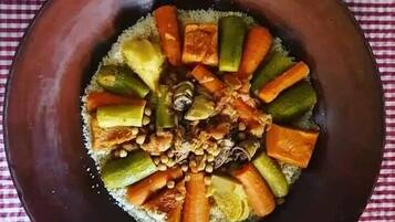 Um prato marrom escuro com um prato de legumes coloridos sobre uma toalha de mesa xadrez.