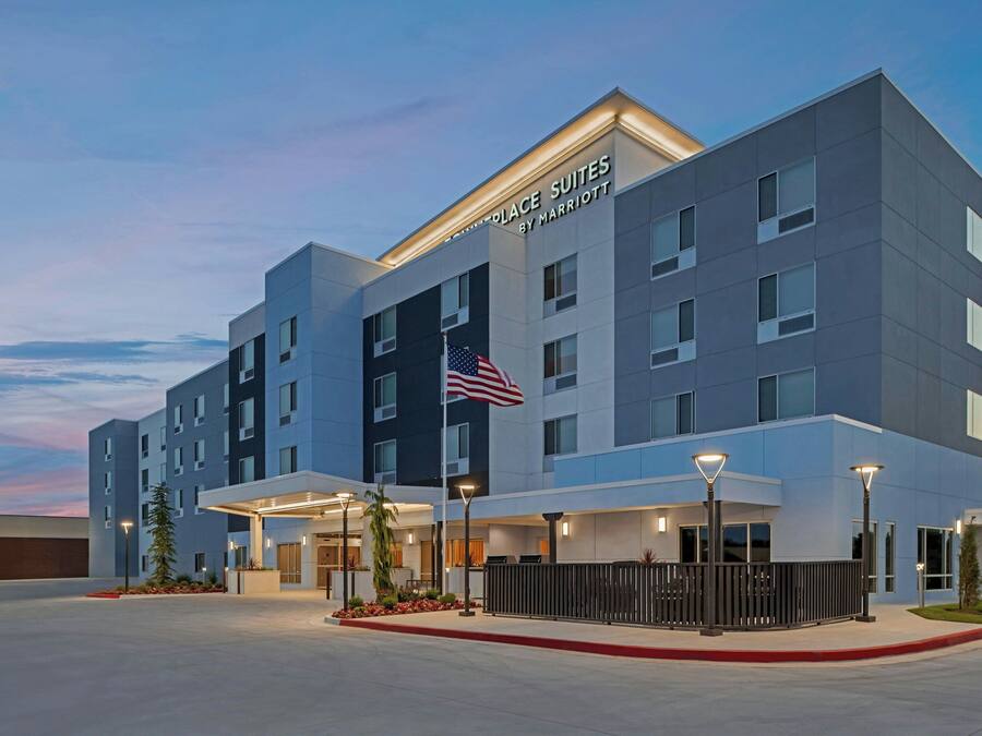 Um hotel moderno com telhado plano, vários andares e uma bandeira americana em destaque.