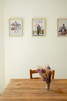 Uma mesa de jantar com um vaso de flores e três quadros na parede.
