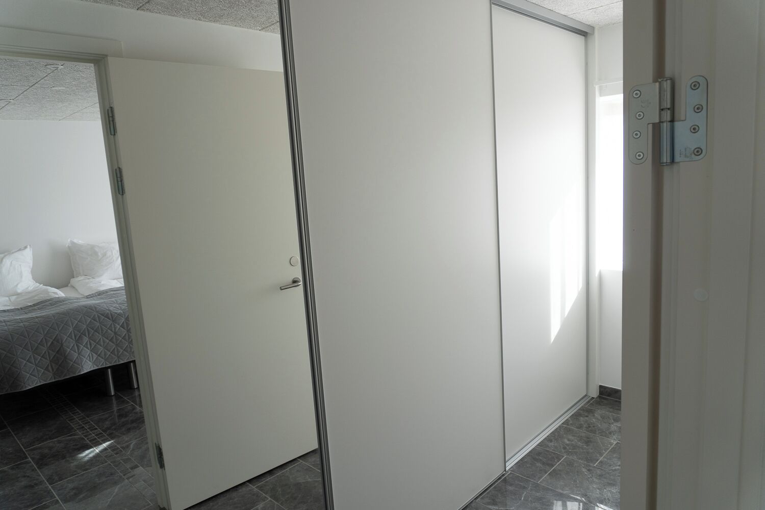 Quarto com cama, guarda-roupa e porta com puxador.