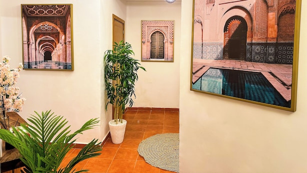 Corredor com três quadros emoldurados retratando cenas arquitetônicas, uma planta em vaso e uma luminária moderna.