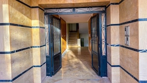 Um corredor com paredes estampadas e chão em padrão herringbone, que leva a uma escadaria.