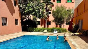Piscina retangular com água azul cristalina, rodeada por um deck ladrilhado.