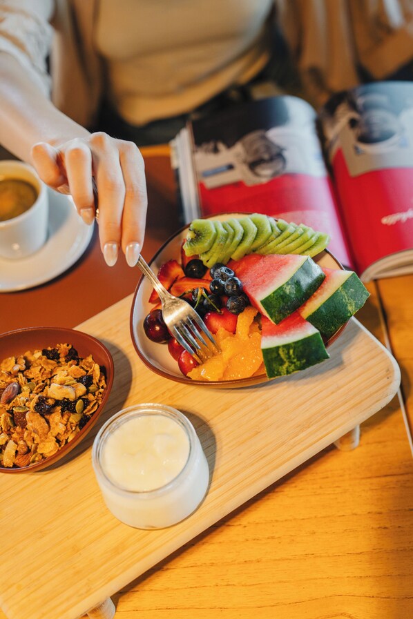 Uma bandeja de café da manhã com tigela de cereal, copo de leite e prato de frutas.
