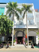 Um hotel com entrada notável, palmeiras e uma placa com a inscrição 'MACALLAN HOTEL'.