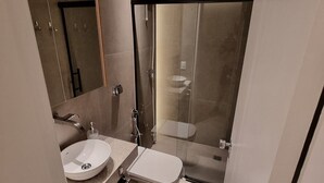Uma casa de banho moderna com chuveiro em cabine de vidro, uma pia e sanita.