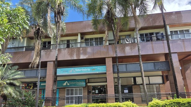 Edifício de vários andares com uma clínica veterinária no andar térreo, exibindo uma placa com o nome e os serviços da clínica.
