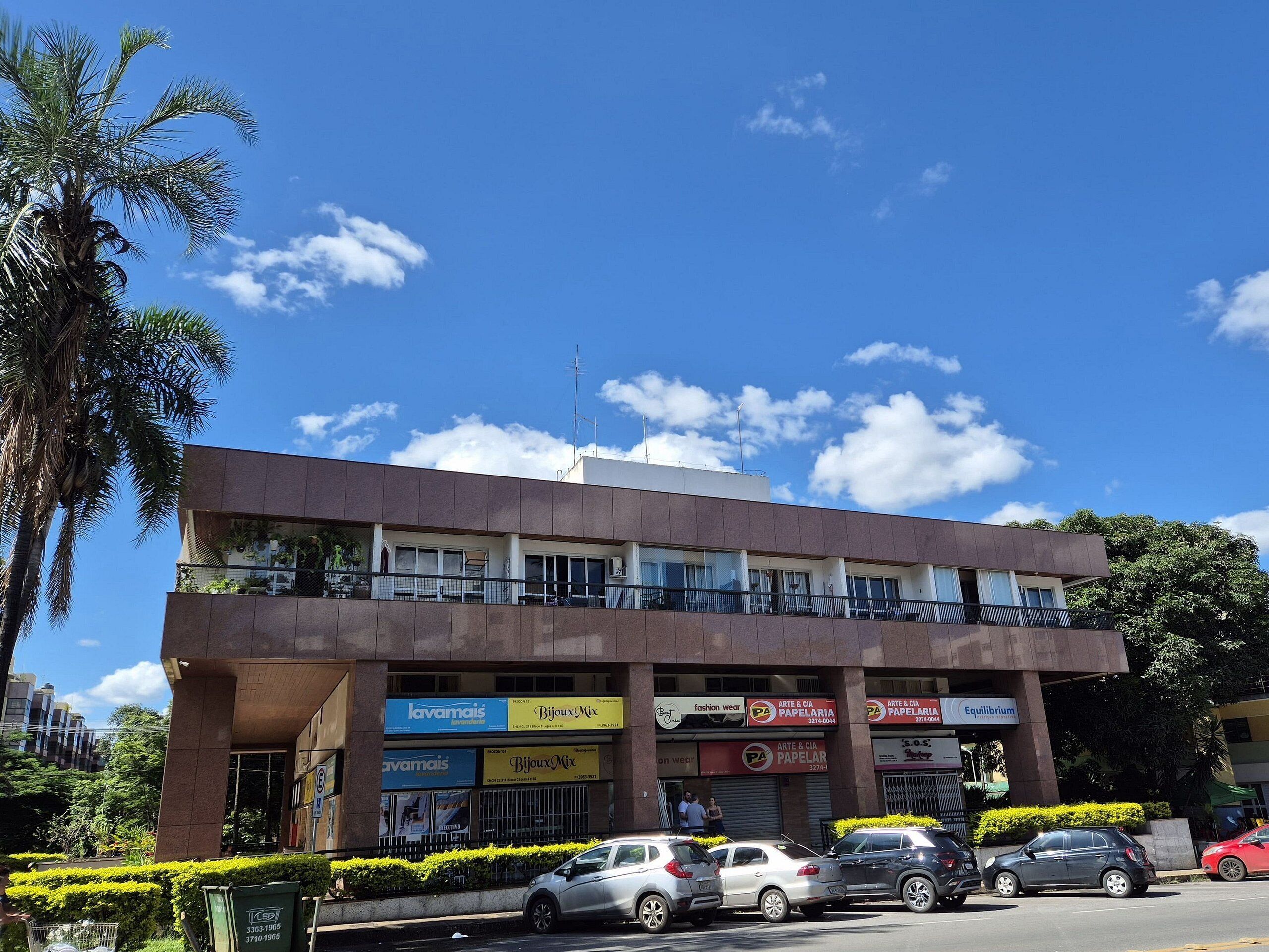 Um edifício de vários andares com diversas lojas no andar térreo, incluindo 'Kavamas' e 'BijouxMix'.