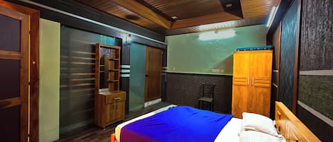 Quarto com cama, guarda-roupa de madeira e armário com espelho.
