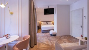 Quarto de hotel moderno com uma cama, mesa de cabeceira e televisão fixada na parede.
