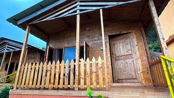 Uma cabana de madeira com varanda, cerca de madeira e uma porta.
