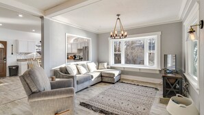 Uma sala de estar moderna com um sofá seccional, um tapete estampado e uma janela grande que proporciona iluminação natural.