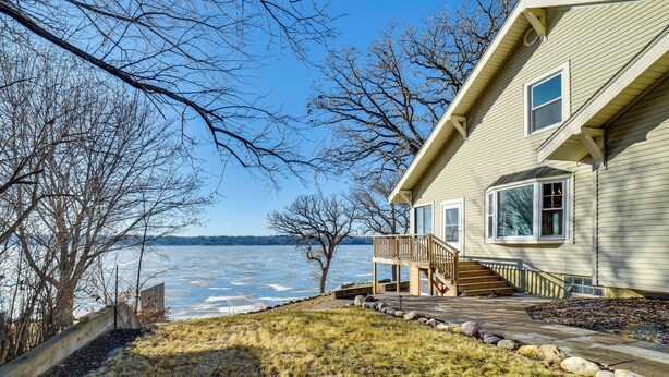 Uma casa com varanda e vista para um lago congelado.